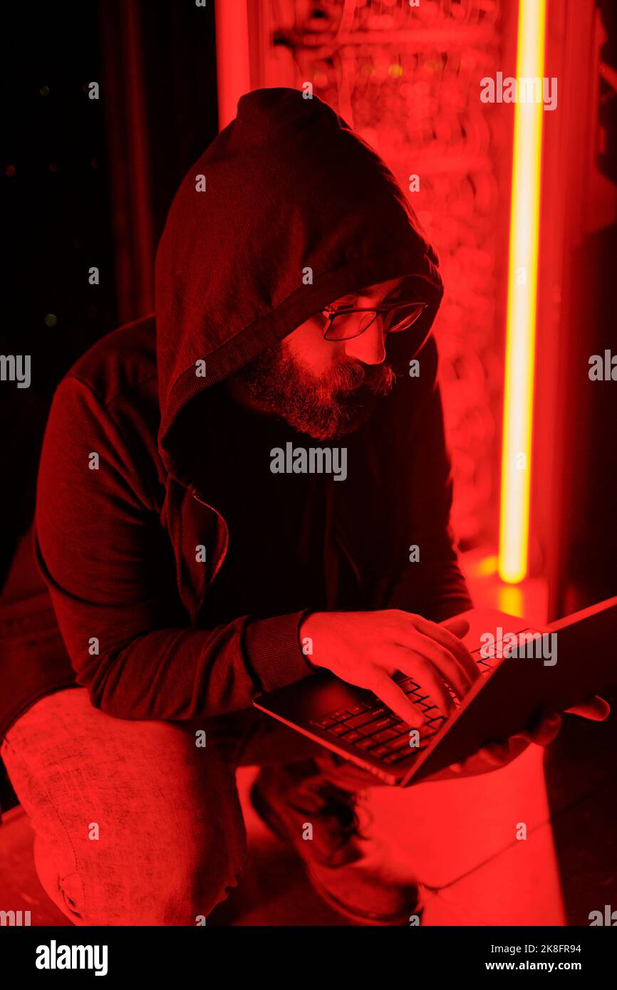 Hacker using laptop crouching in data center Stock Photo - Alamy