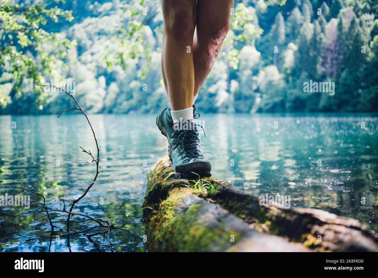 Woman wearing hiking boot walking on tree log by Lake Levico Stock ...