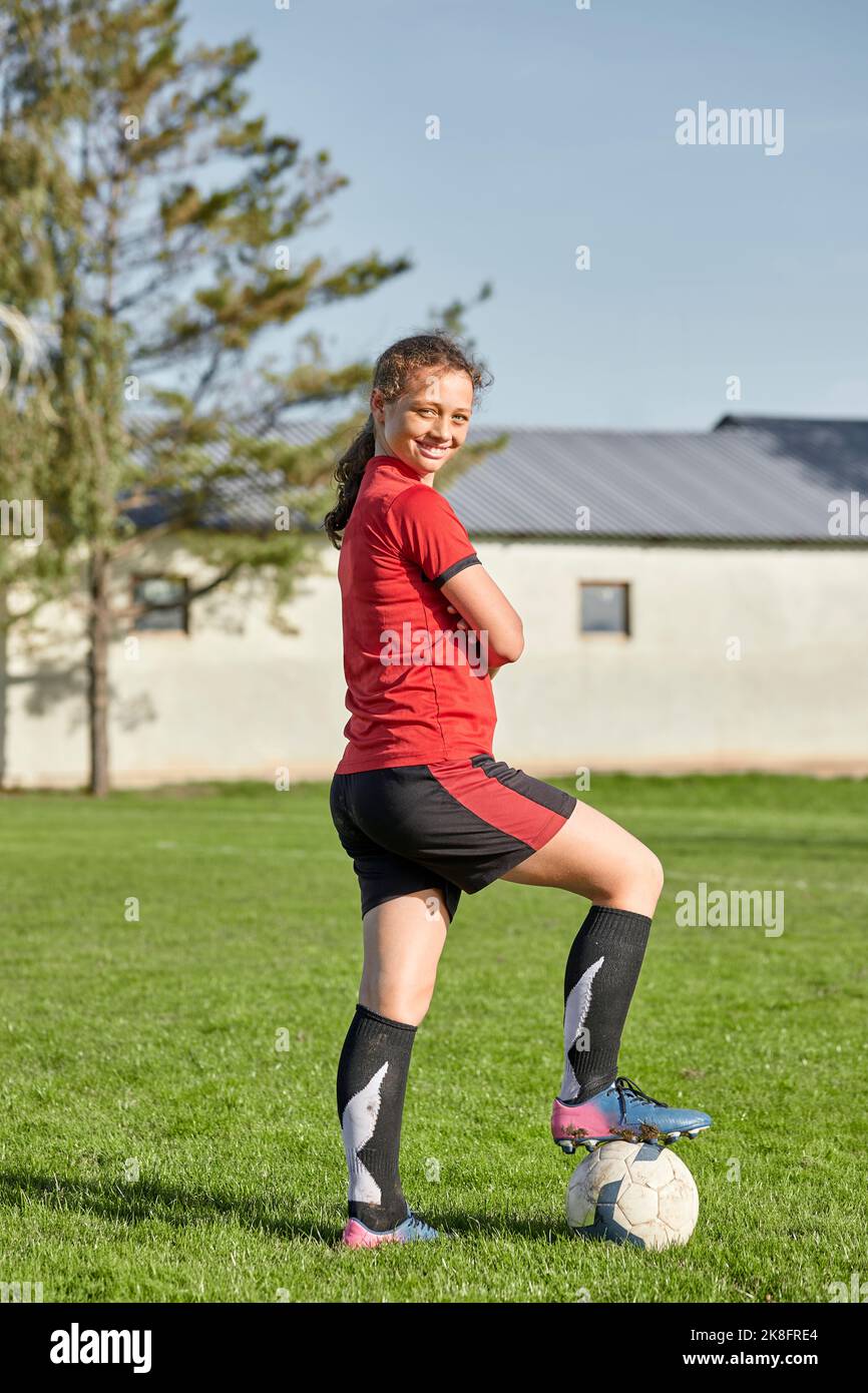 Happy girl standing with soccer ball on field Stock Photo - Alamy