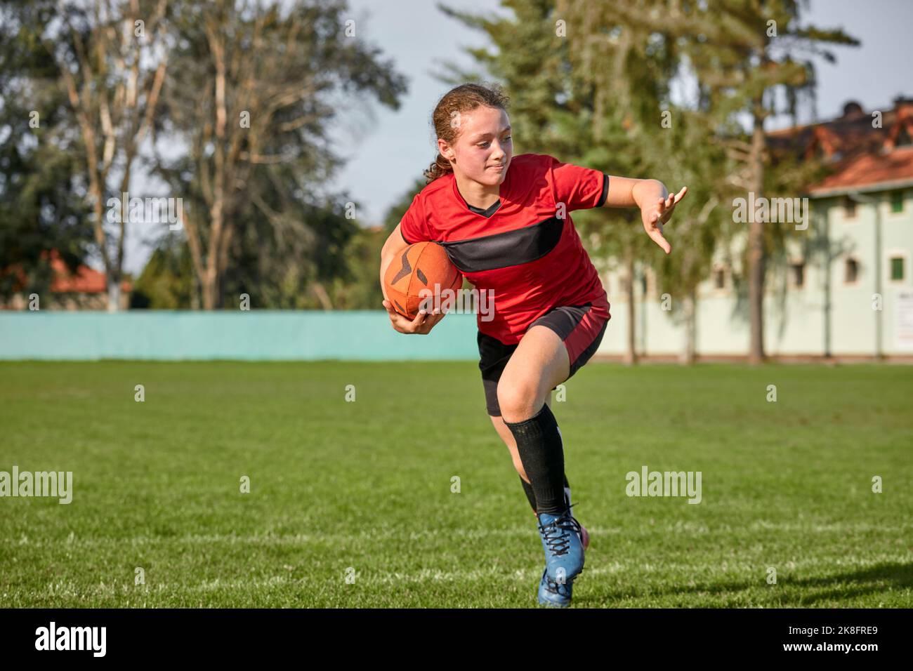 Girl with rugby ball running on sports field Stock Photo - Alamy