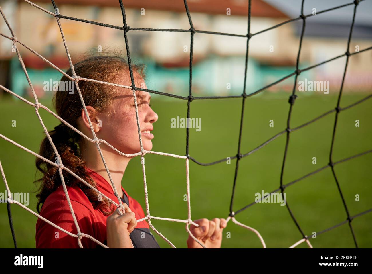 Girl standing behind net on field on sunny day Stock Photo - Alamy