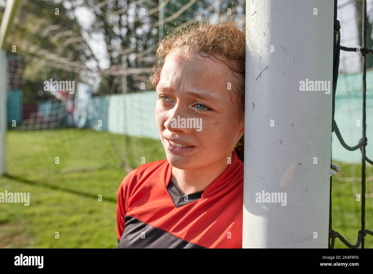 Sad girl leaning on goal post at field Stock Photo - Alamy