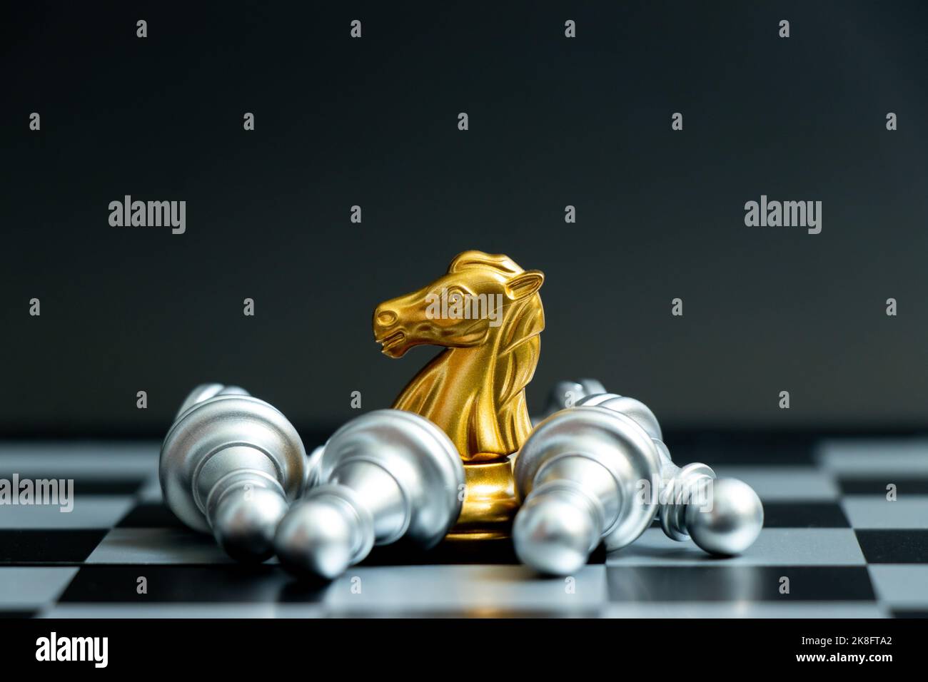 Gold horse knight in chess game with the lying silver team on black ...