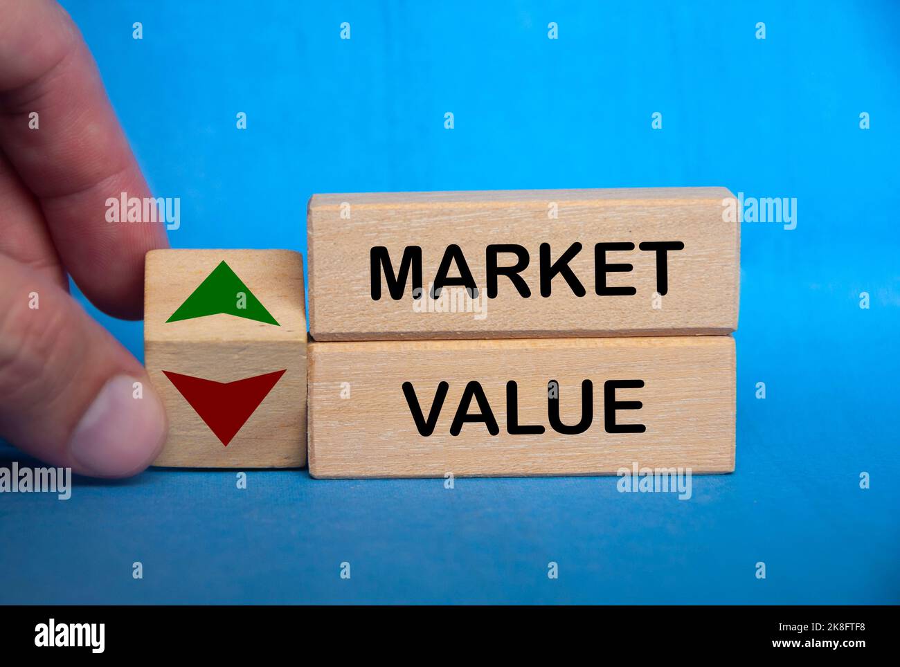 Hand switching up and down arrow with market value text on wooden ...