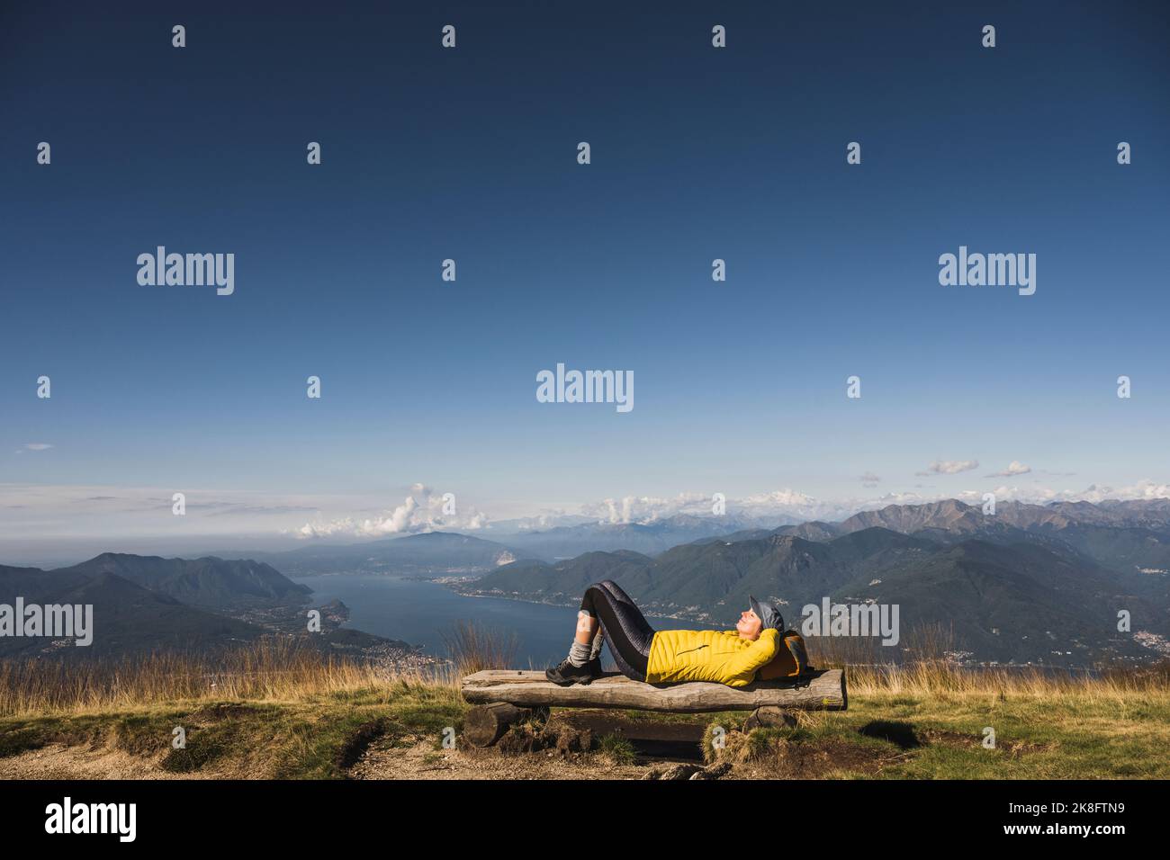 Woman wearing cap relaxing on bench under sky Stock Photo - Alamy