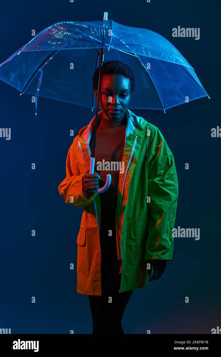 Hipster woman in raincoat with umbrella in neon light Stock Photo - Alamy