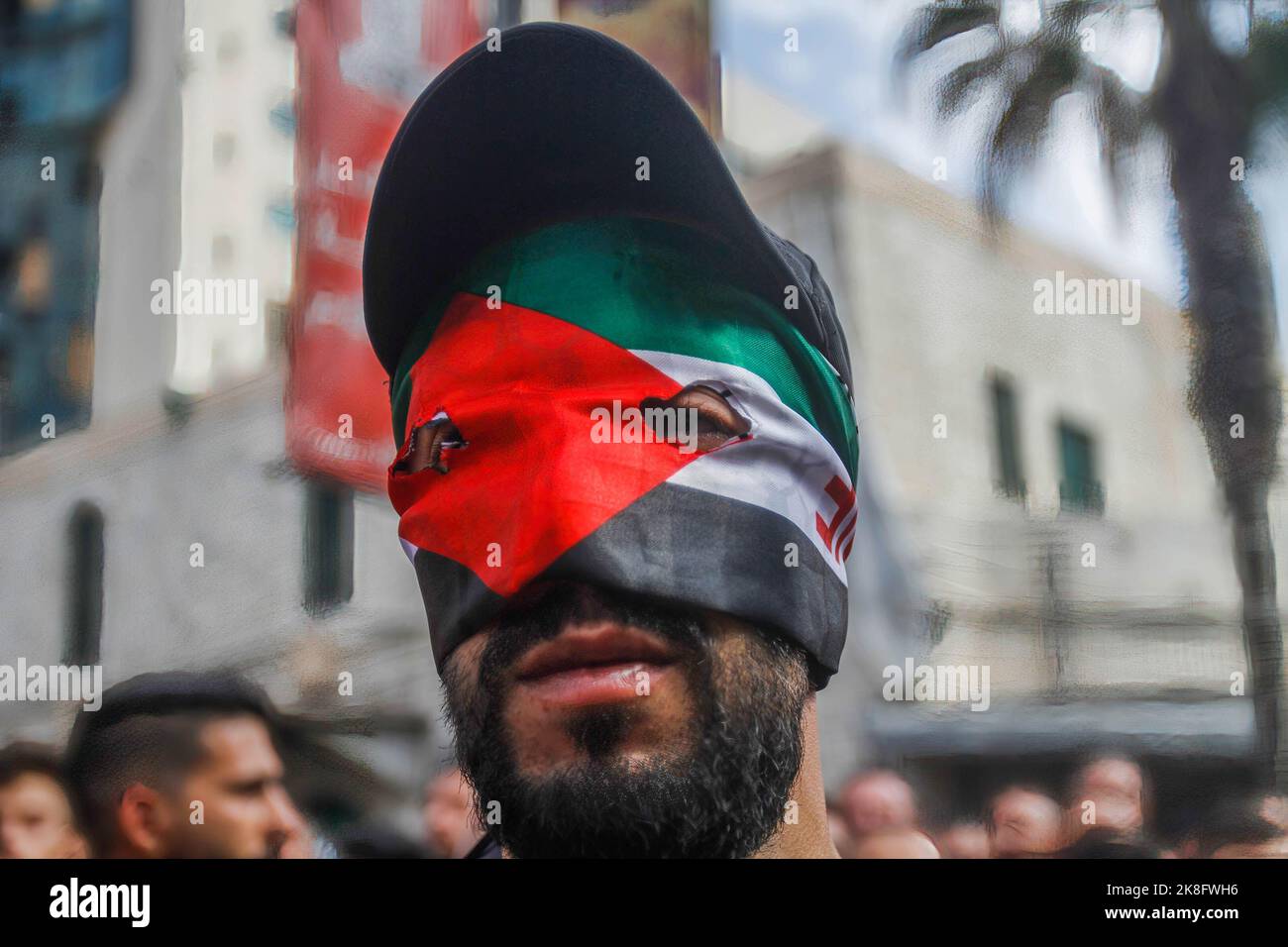 A man wears a mask in colors of the Palestinian flag during the funeral ...