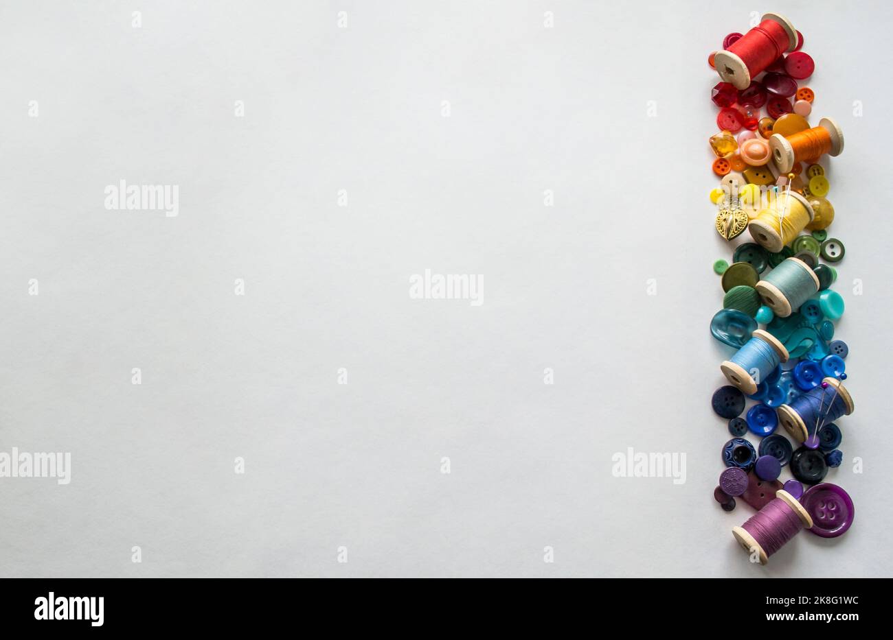 A lot of buttons and reels with colorful threads, laid out on a white ...
