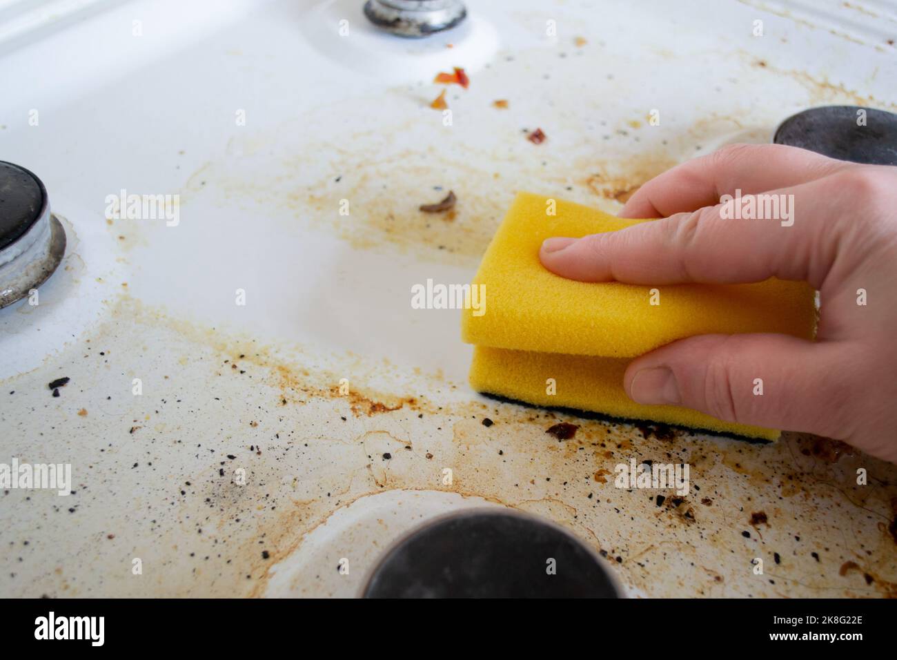 A hand with a yellow wash sponge washes the very dirty greasy surface ...