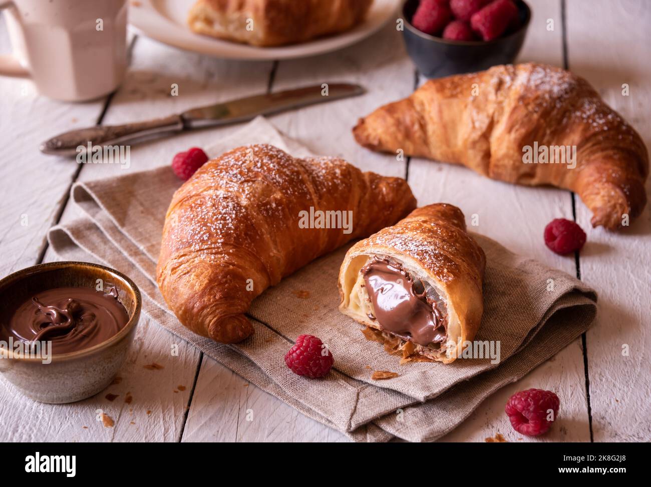 Delicious sweet croissant with chocolate and fruit on white wooden ...