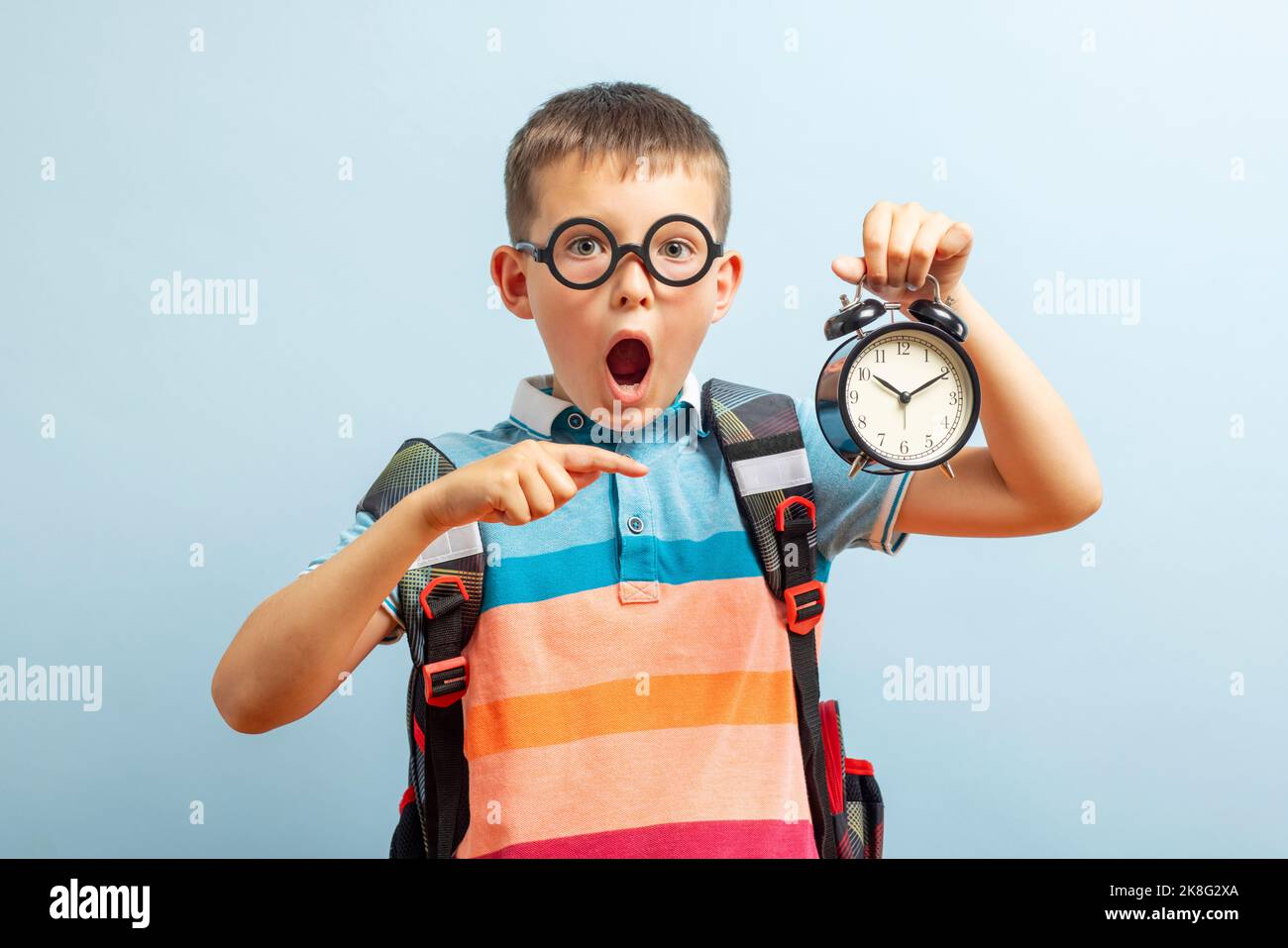 Shocked schoolboy holds an alarm clock in his hand Stock Photo - Alamy