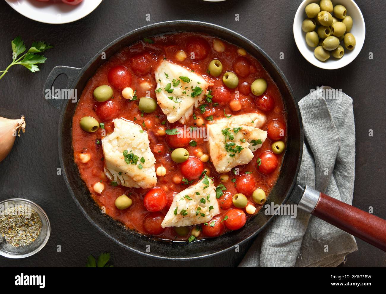 Cod stew with chickpeas, cherry tomatoes and olives in skillet over ...