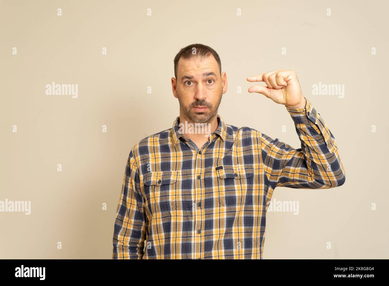 Unhappy latin bearded man looking disappointed and showing small ...