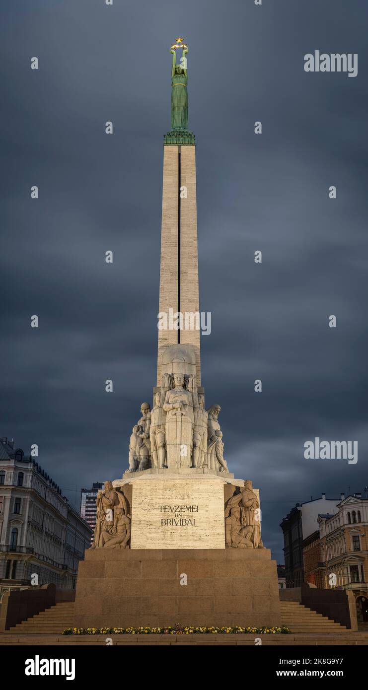 Monument of freedom in Riga at night. Woman holding three gold stars ...