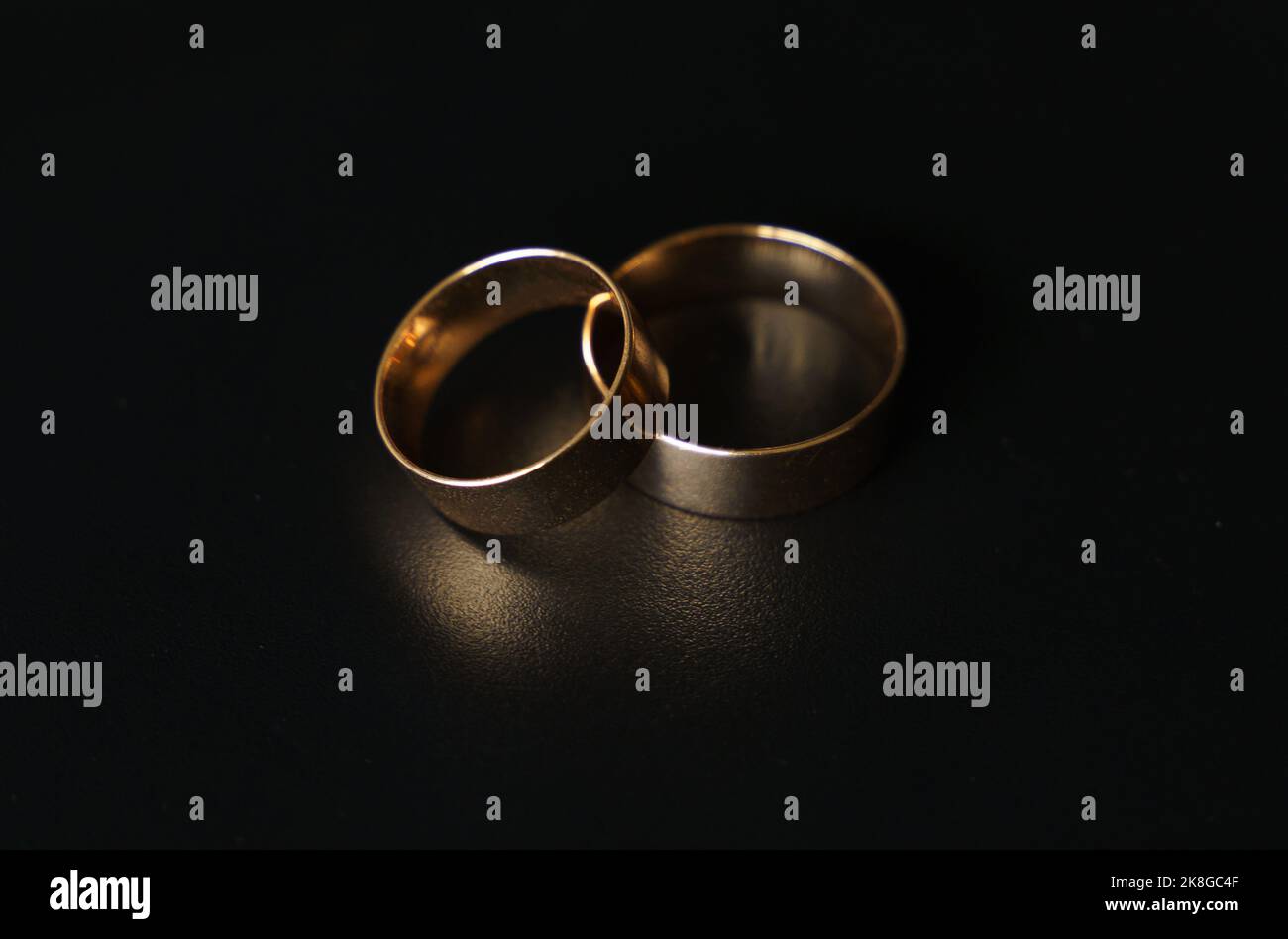 Wedding rings on a black background in the rays of light. wedding ...