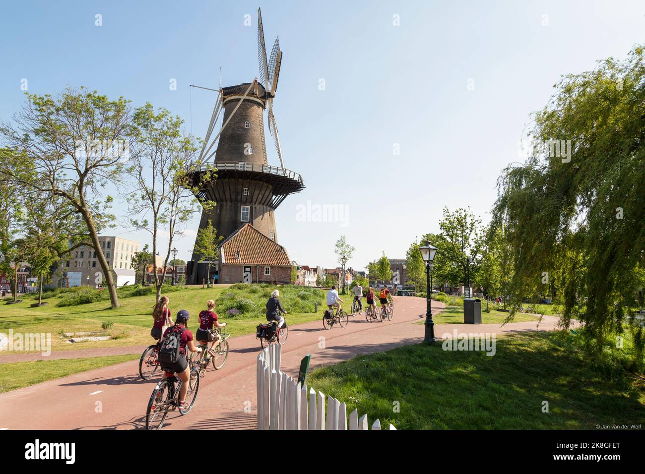 Cyclists ride on the cycle path past the mill to the center of the city of Leiden Stock Photo ...