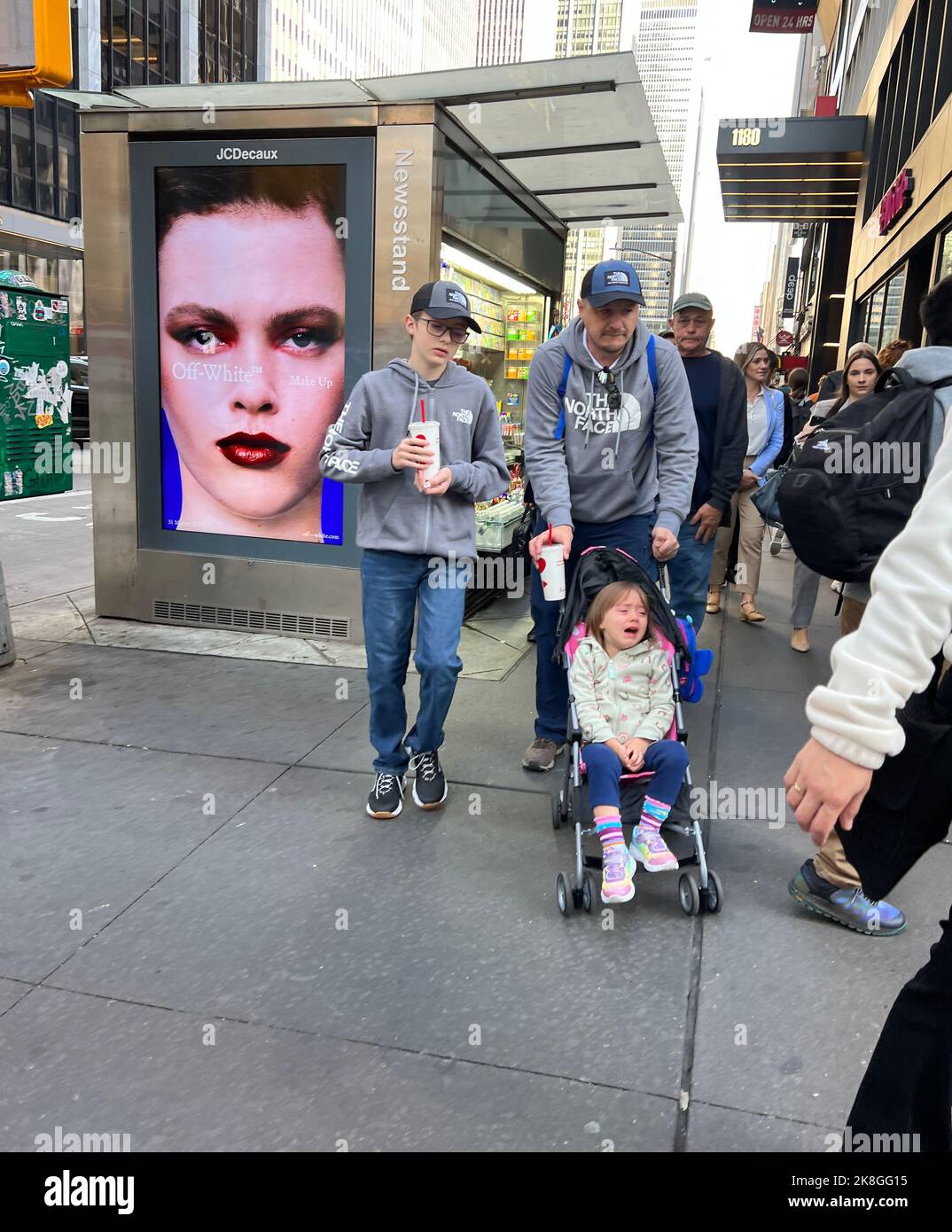 Tired child being pushed down the street by dad on Broadway in midtown ...