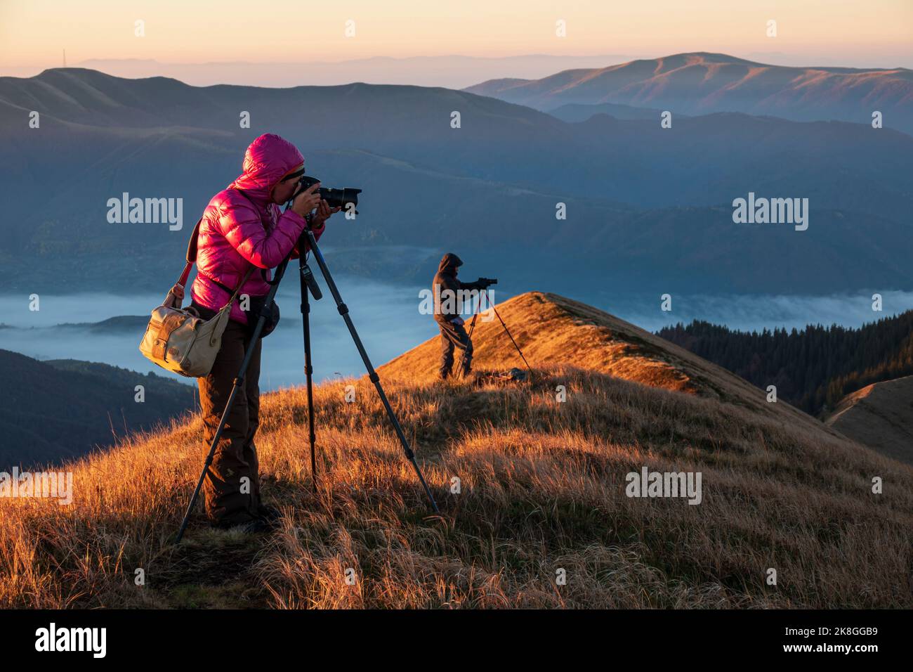 Landscape photographers with the tripods on the mountain top early in the morning. Creating ...