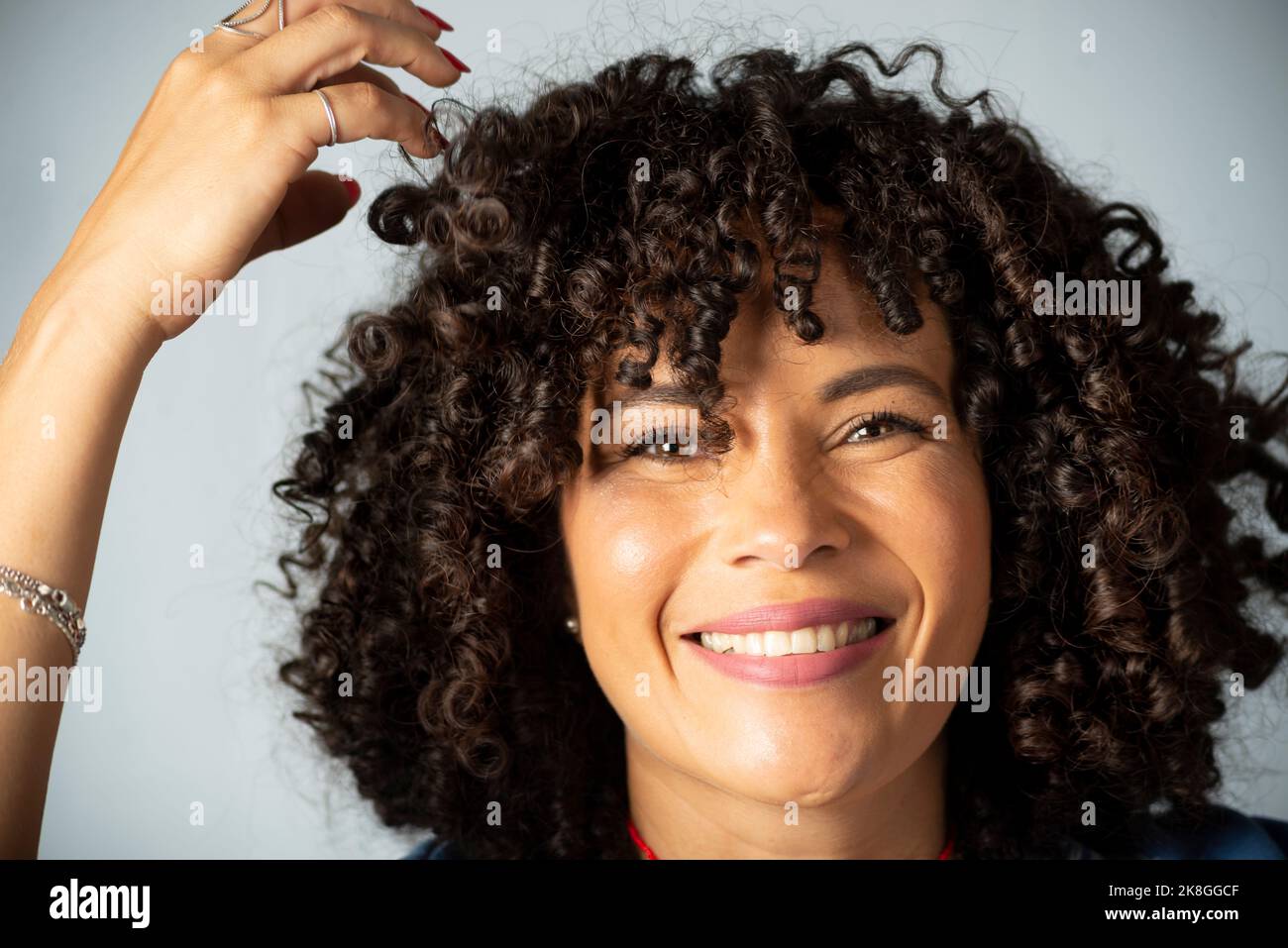 Portrait Of Smiling Beautiful Curly Hair Model Against Light Background