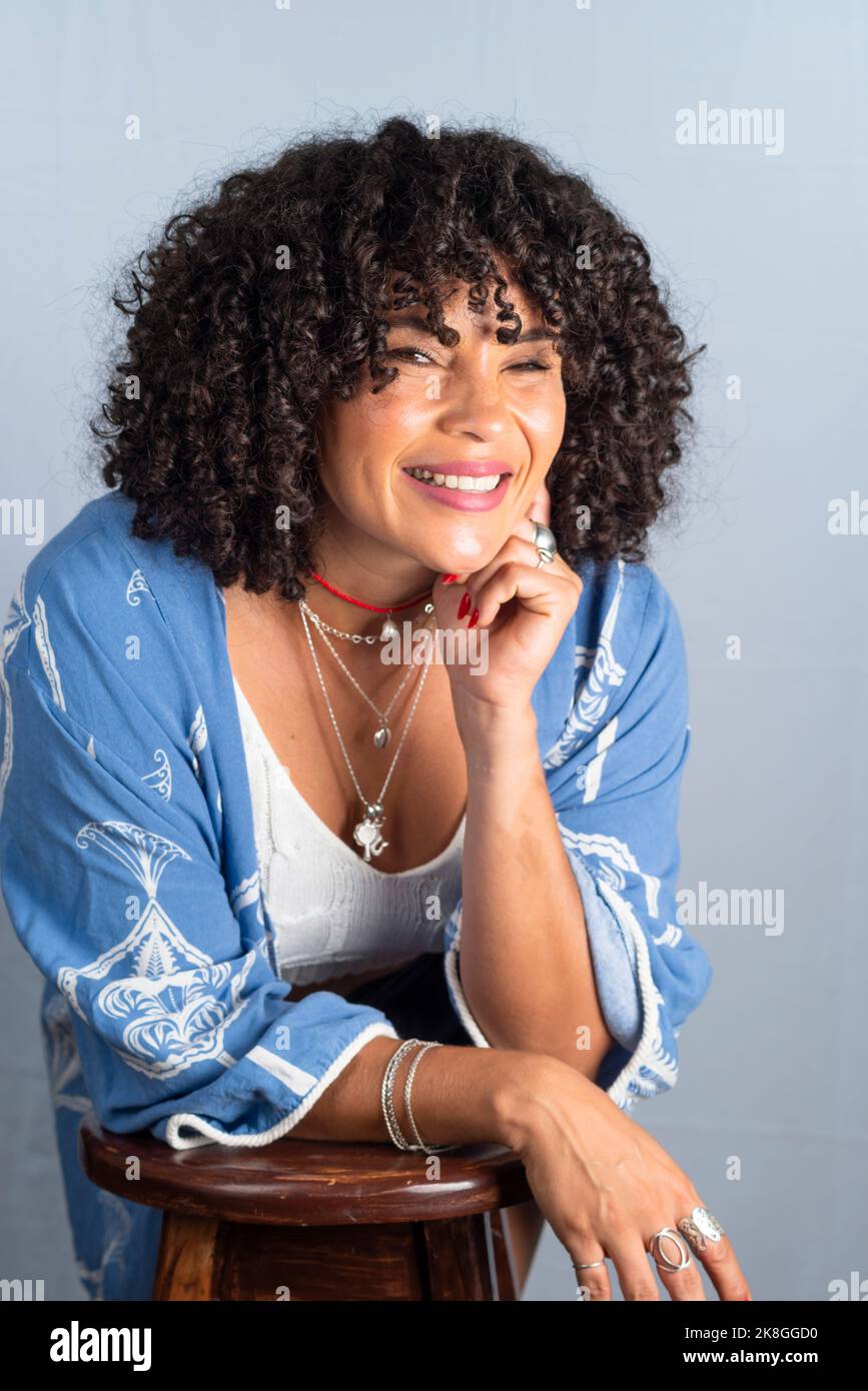 Portrait of smiling beautiful curly hair model against light background ...