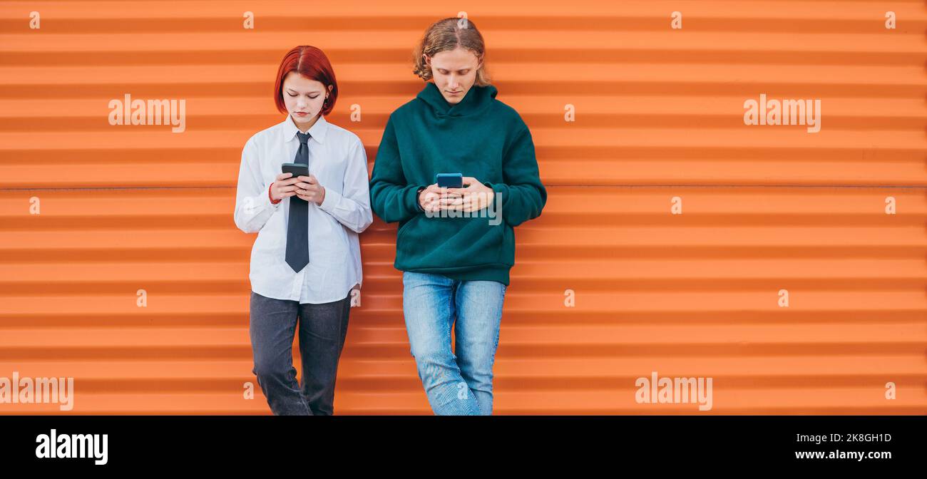 Two caucasian teen friends boy and a girl browsing their smartphone ...