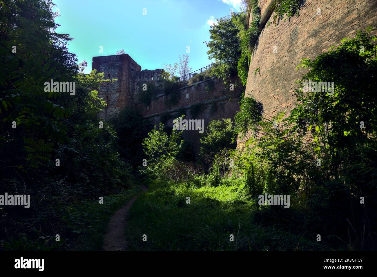 Bend in a narrow trail of a forest next to an old fortification wall on ...
