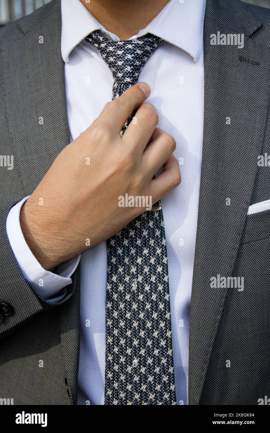 Crop anonymous male entrepreneur in classy suit adjusting tie on white ...