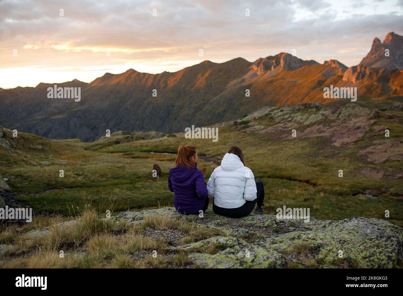Back view of unrecognizable young girlfriends admiring mountain sunset ...