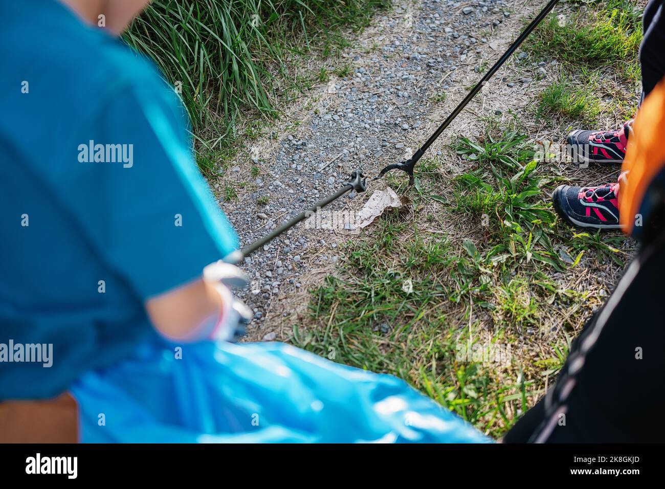 High angle of crop anonymous volunteers collecting trash with sticks on ...