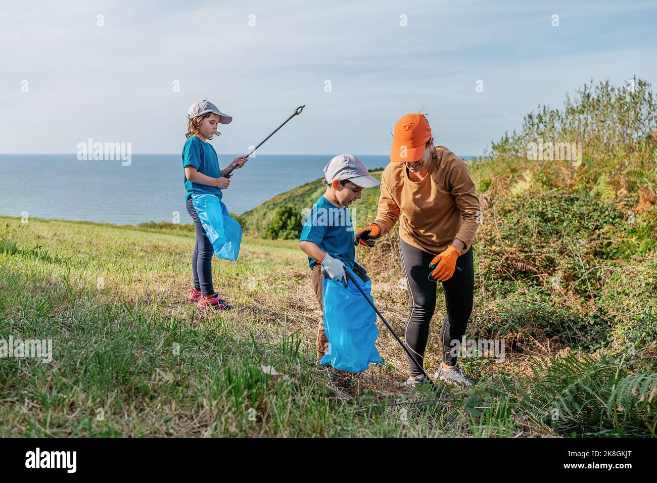 Cleanup volunteers picking up trash in garbage bags with sticks on ...