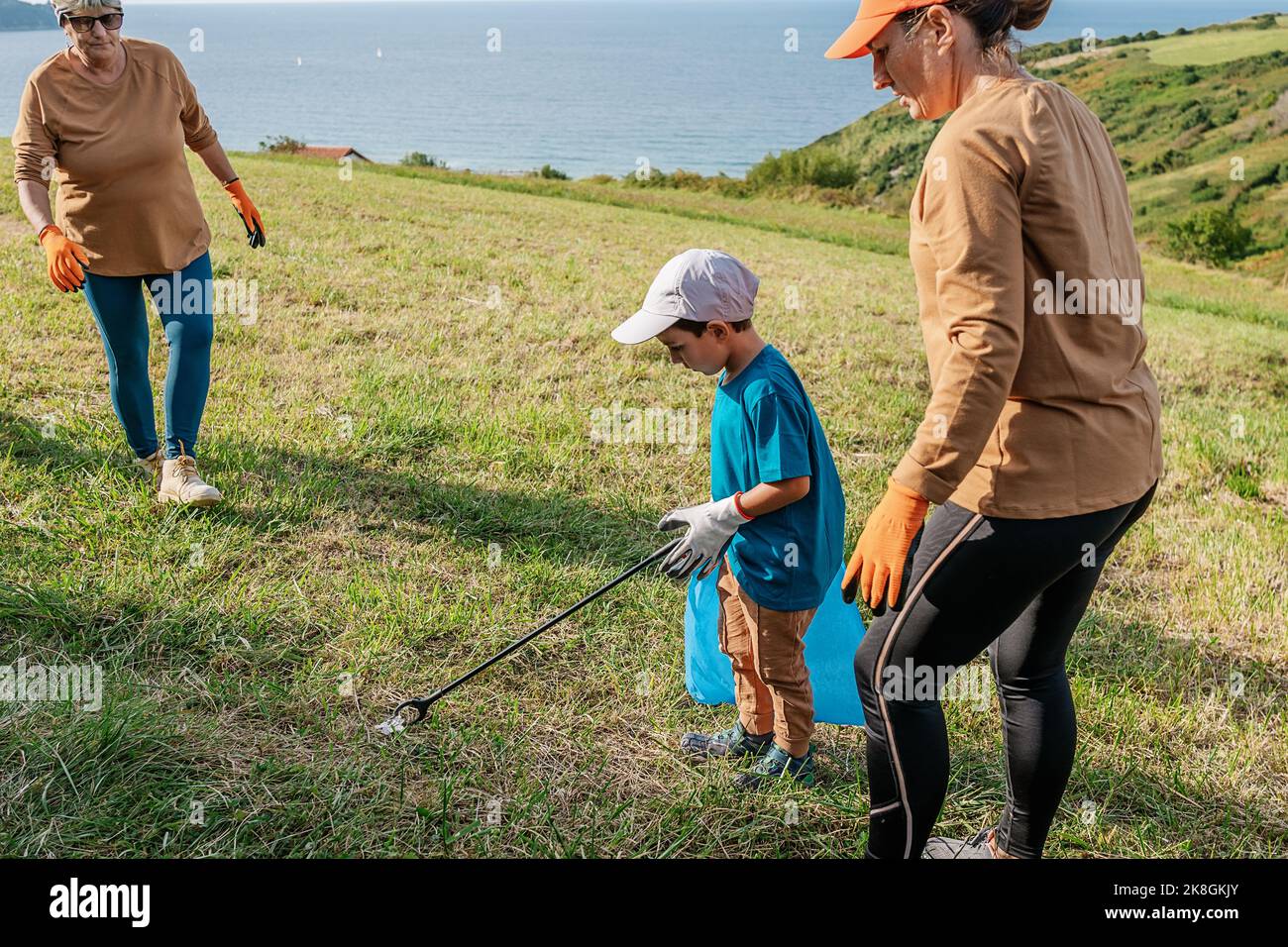 Cleanup volunteers picking up trash in garbage bags with sticks on ...