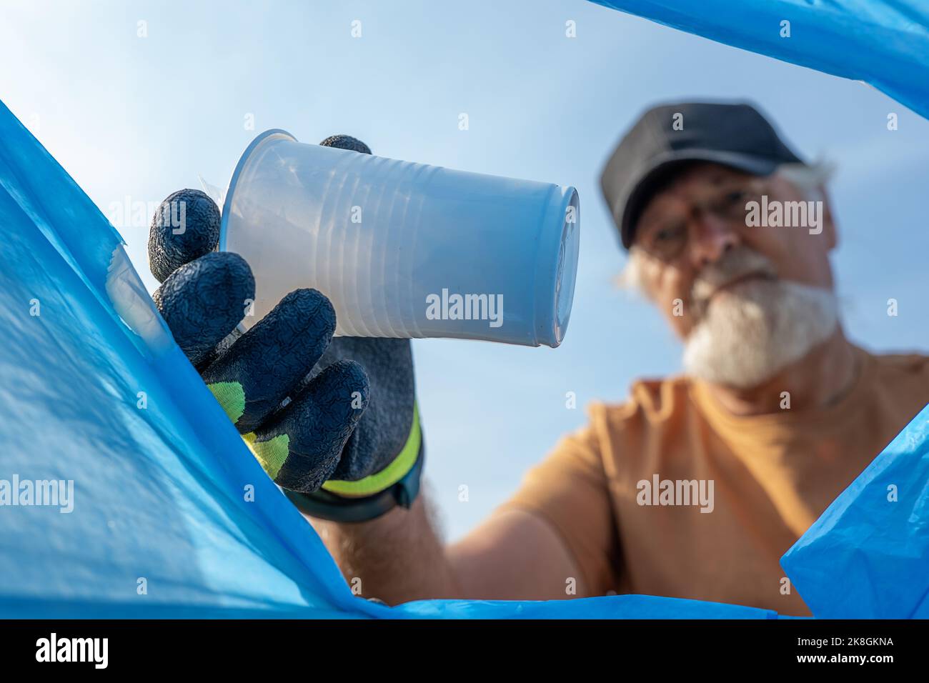 From below of aged bearded male volunteer in cap and protective gloves ...