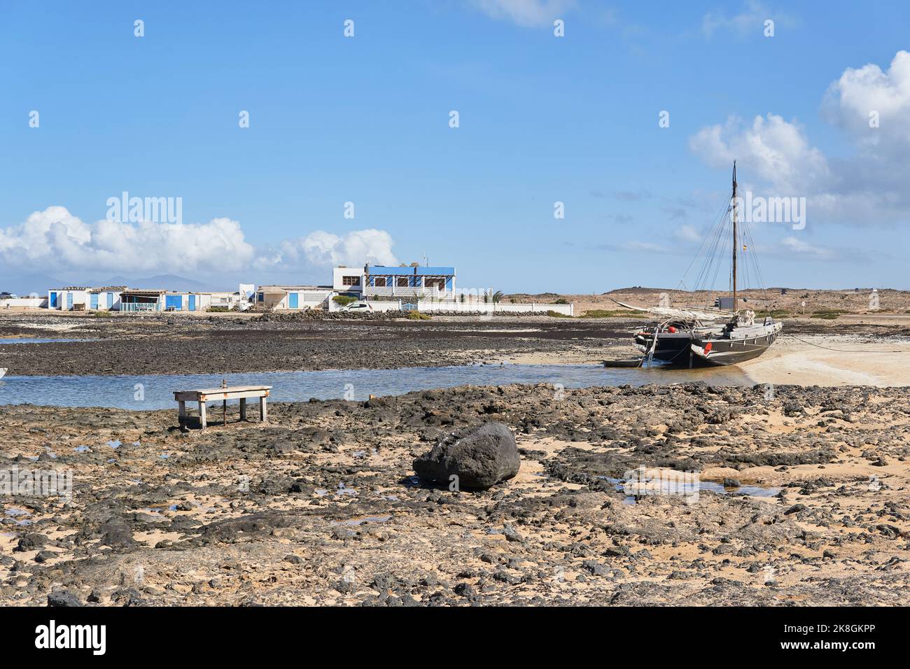 Modern boat moored on sandy beach against cloudy blue sky during low ...