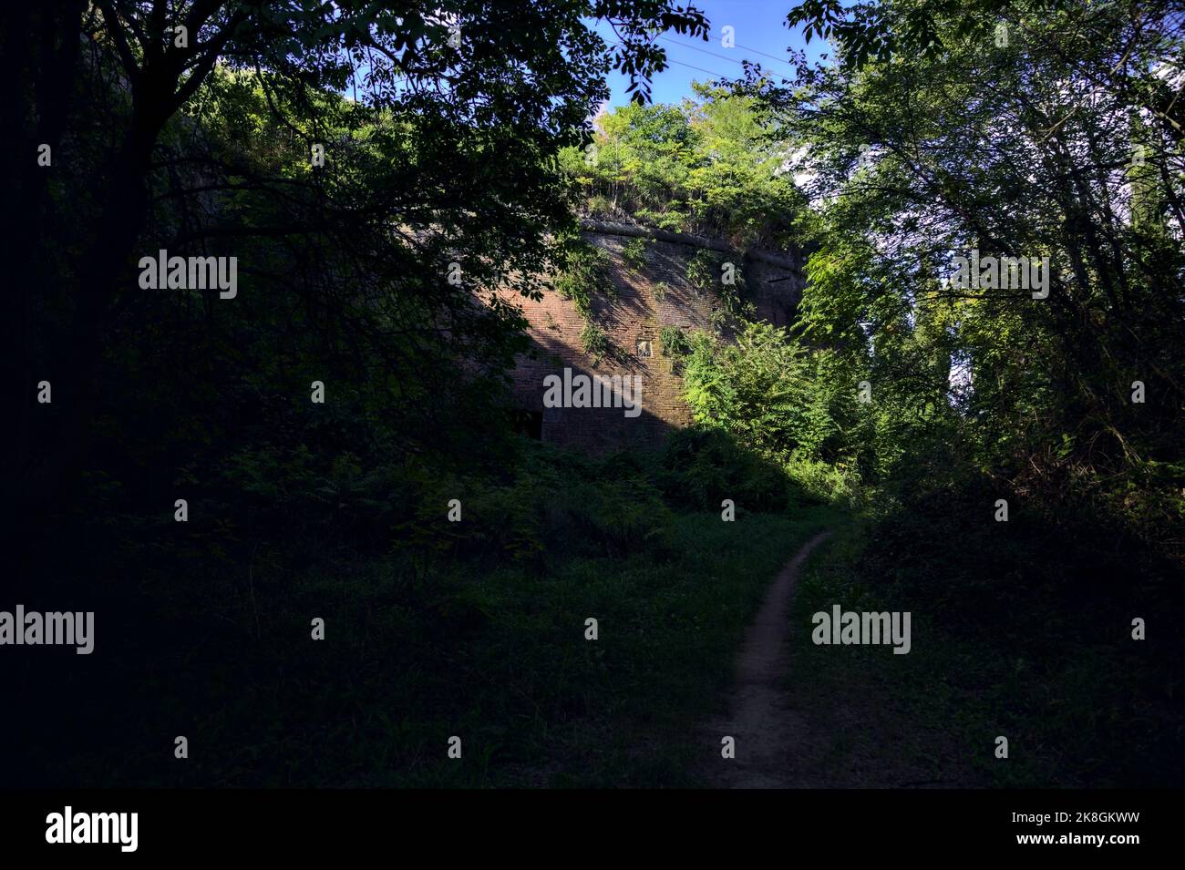 Bend in a narrow trail of a forest next to an old fortification wall on ...