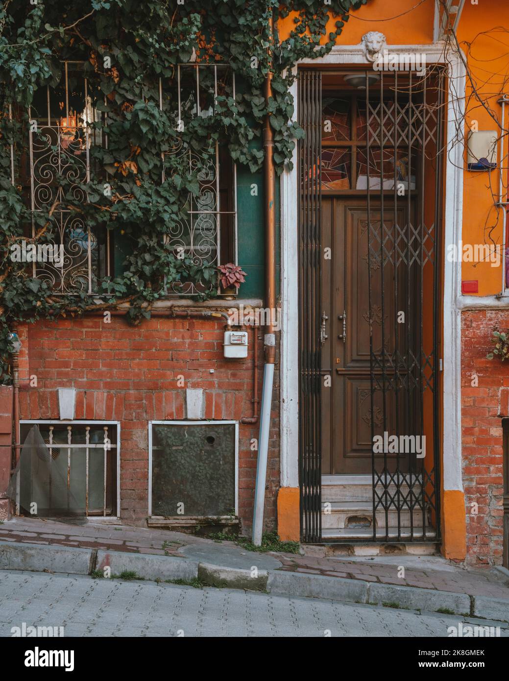 Orange house with metal grating on door and window located near paved ...