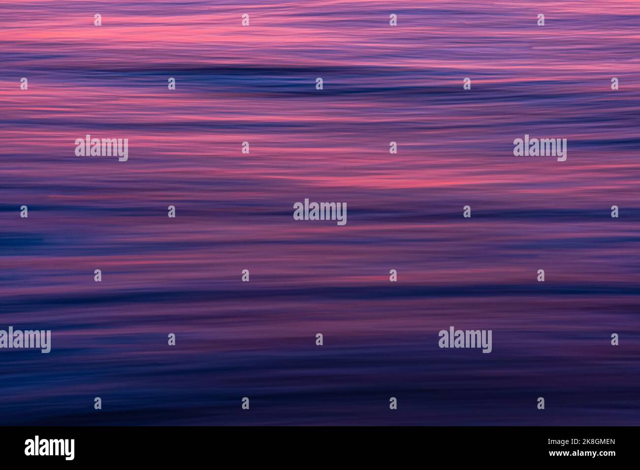 Full frame background of blue sea water rippling and reflecting pink ...