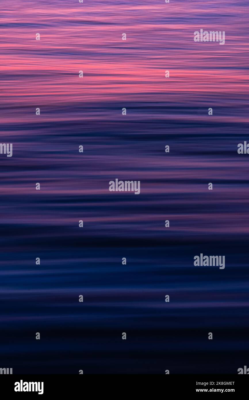 Full frame background of blue sea water rippling and reflecting pink ...