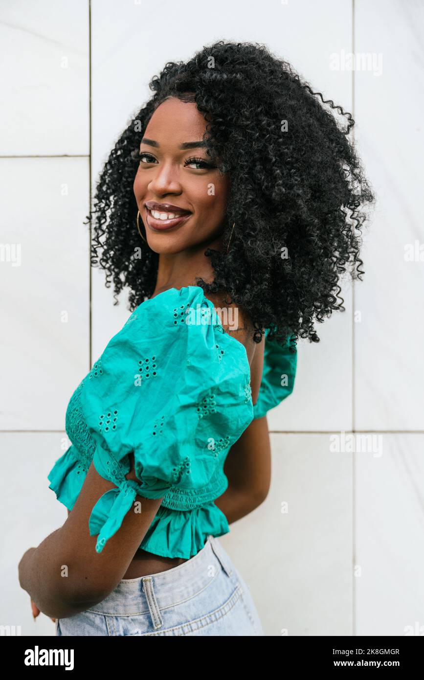 Side view of cheerful ethnic woman with Afro hairstyle and makeup in ...