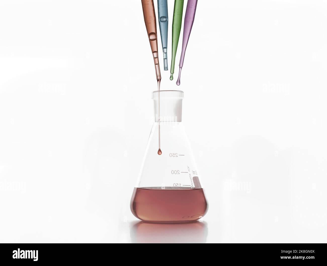 Test droppers with liquids over glass laboratory flask placed on desk ...