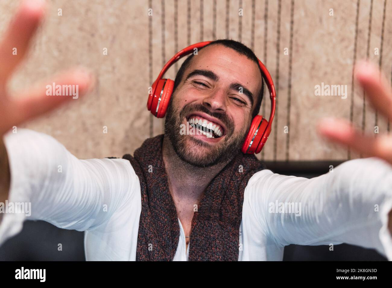 High angle of cheerful male meloman in white shirt smiling and reaching ...