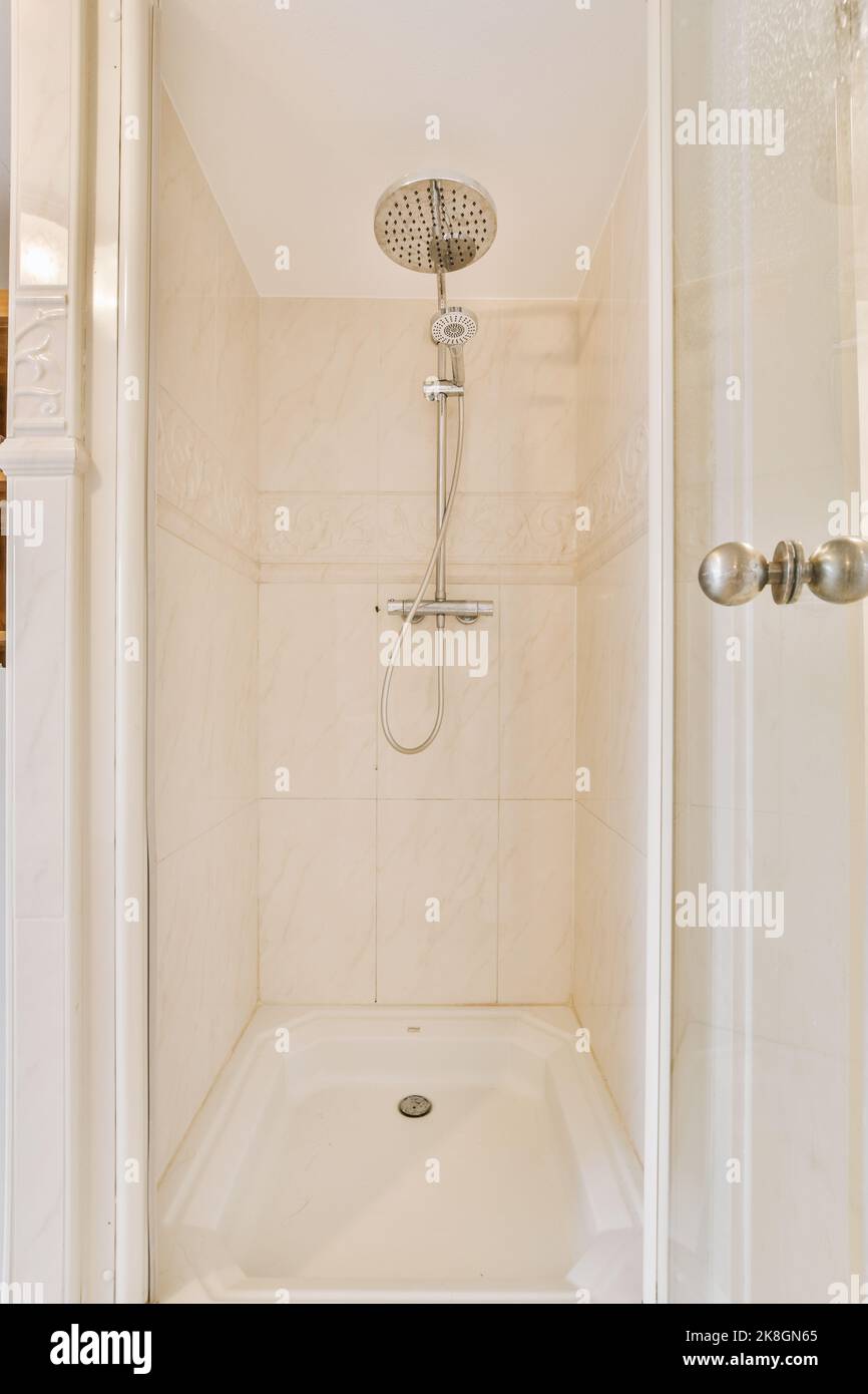 Shower faucets attached to tiled wall near glass partition and ...