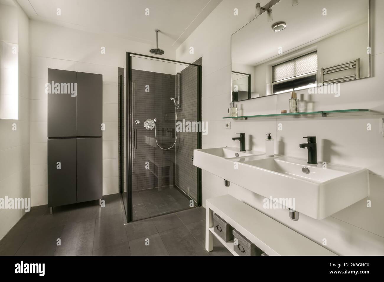 Glass shower cabin in light modern bathroom with white tiled wall and ...