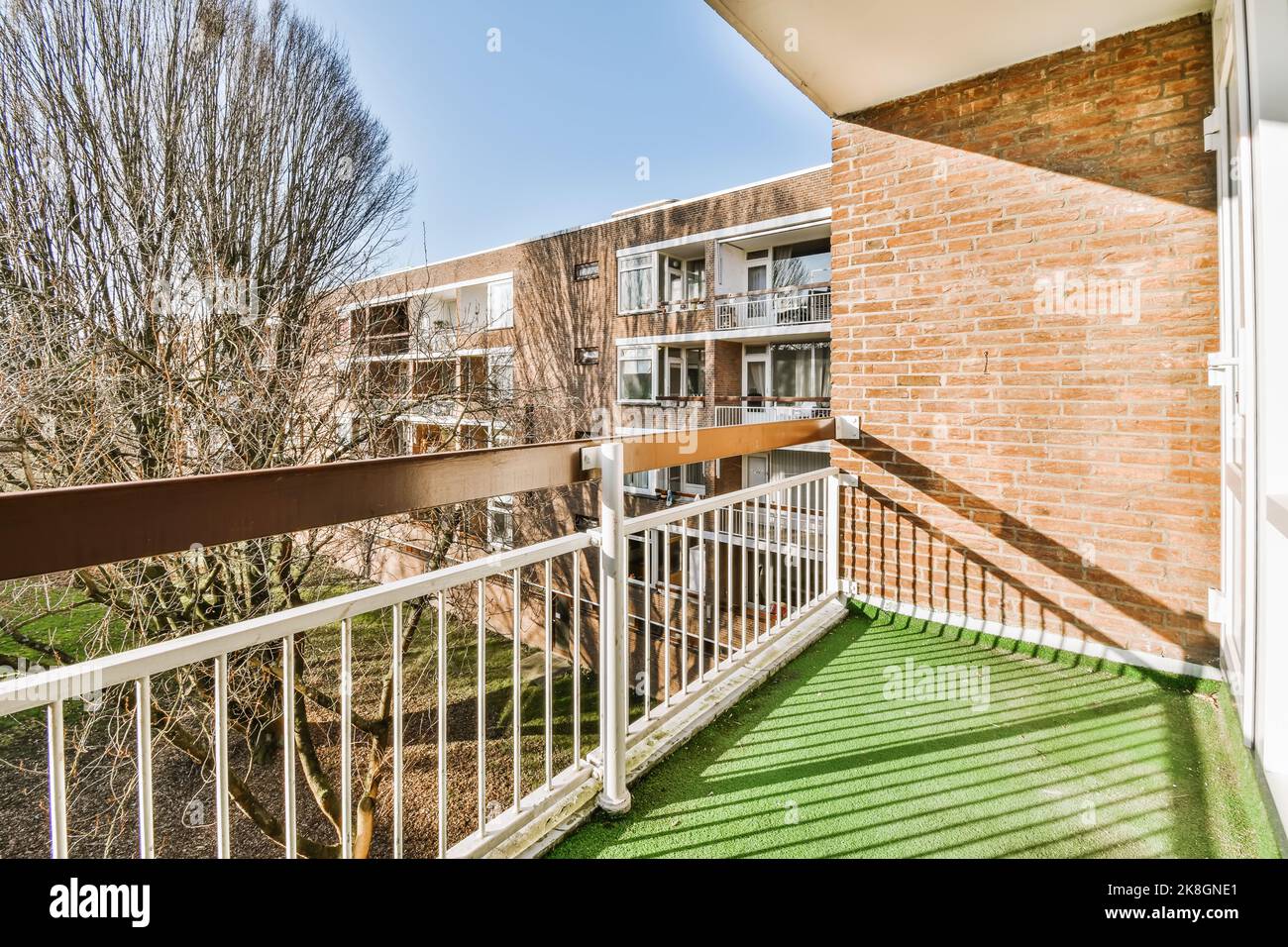 Terrace of building with metal railing against blue sky and residential ...
