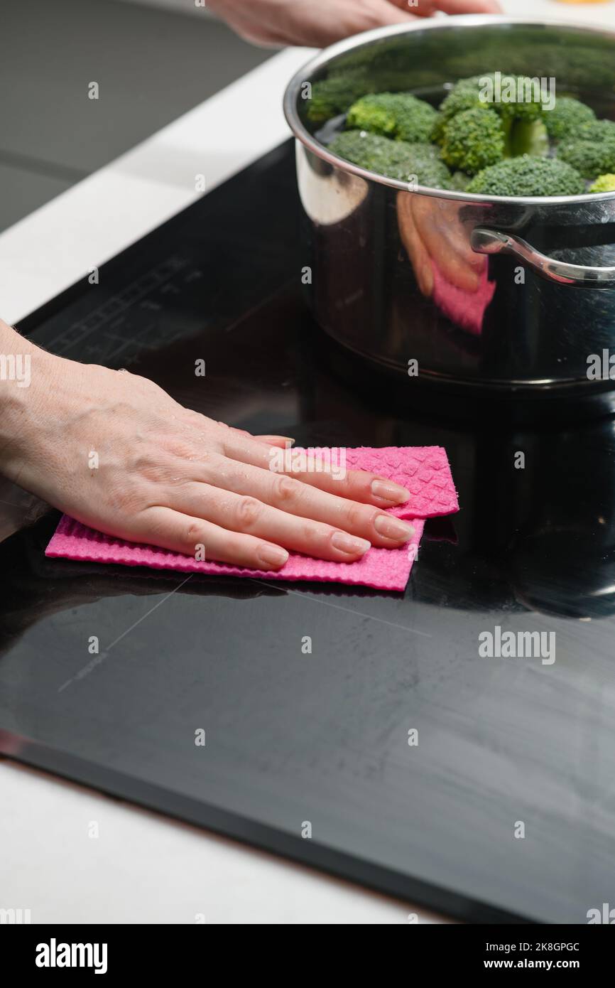 Woman cleaning induction top. Female hand wipes the hob of the ...