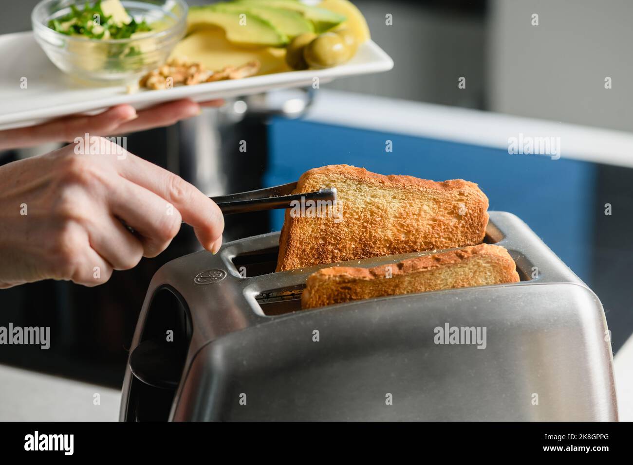 Toaster with toasted bread for breakfast inside. The female hand pulls ...
