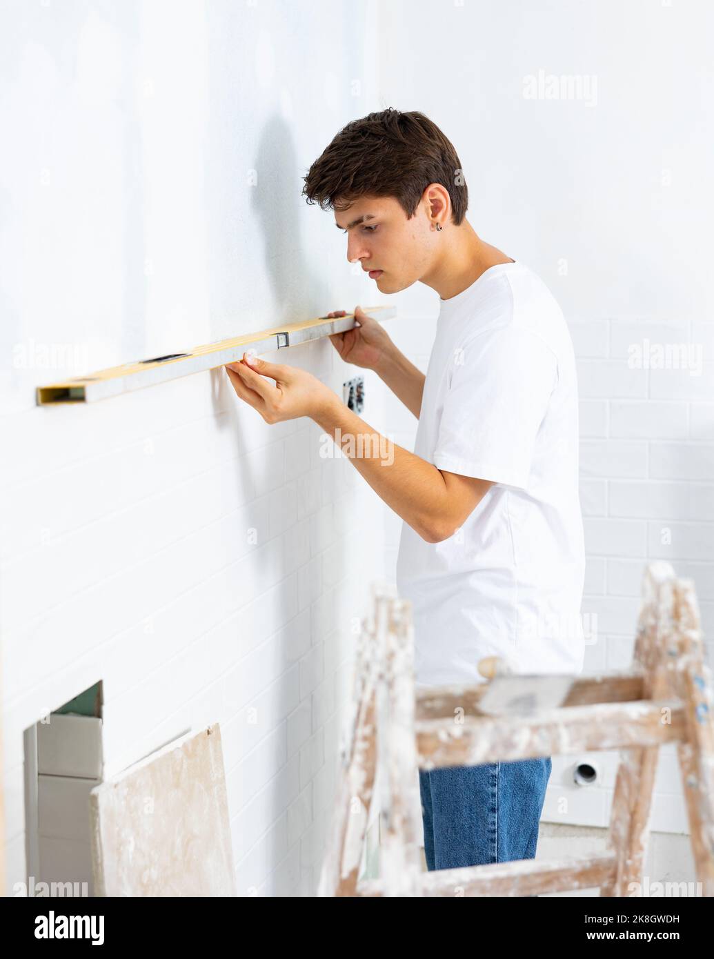 Guy measuring wall flatness with level meter while renovating house ...