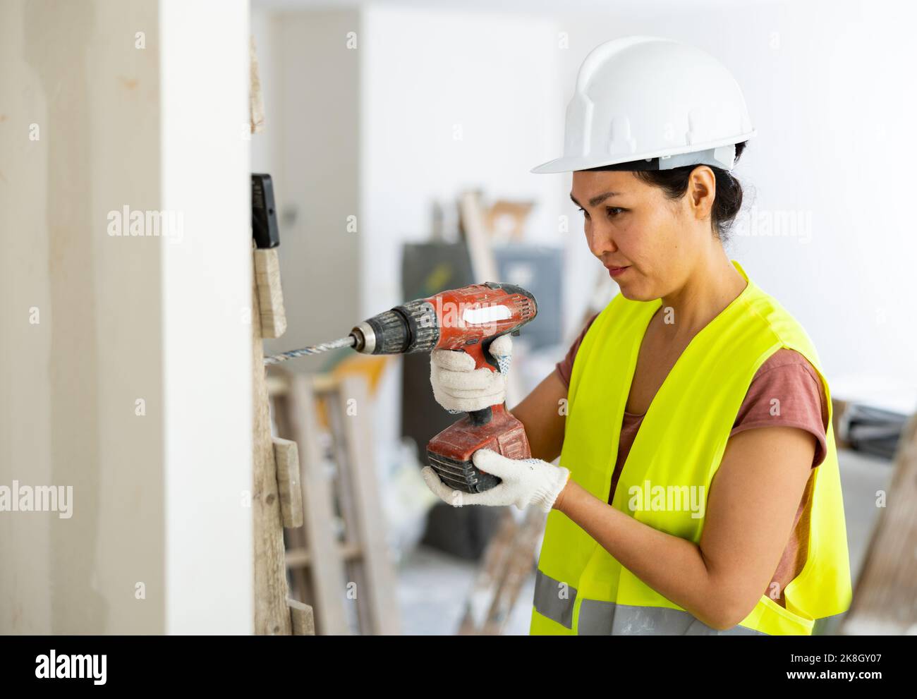 Woman builder using drill to bore hole in wall Stock Photo - Alamy