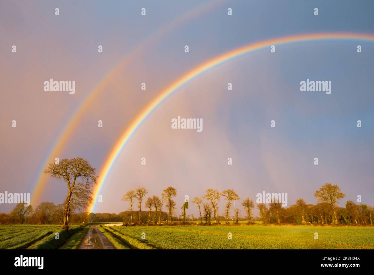 Rural landscape with rainbow over dark stormy sky in a countryside in ...