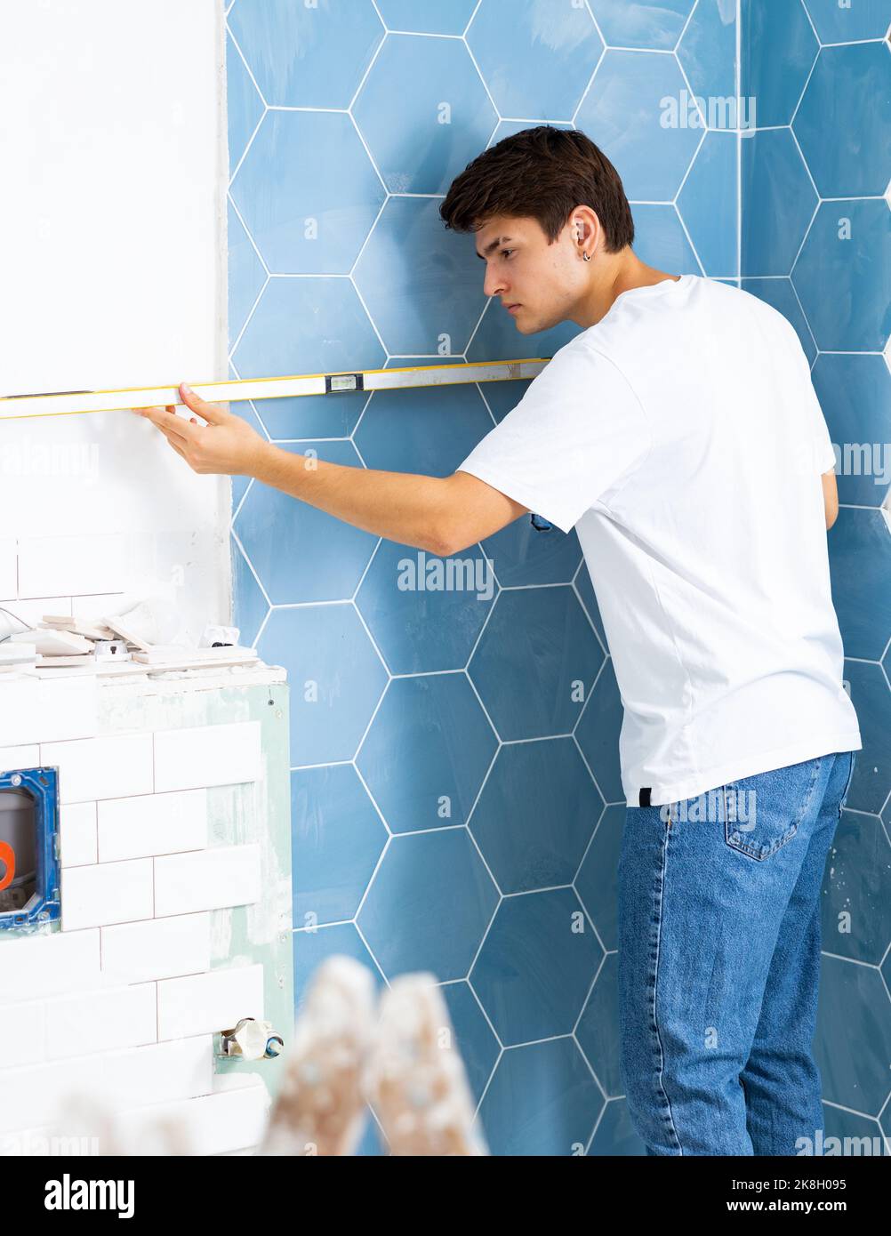 Guy measuring wall flatness with level meter while renovating house ...