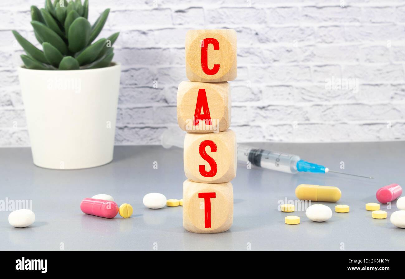 A wooden block with the word CAST stands on a blue background among ...
